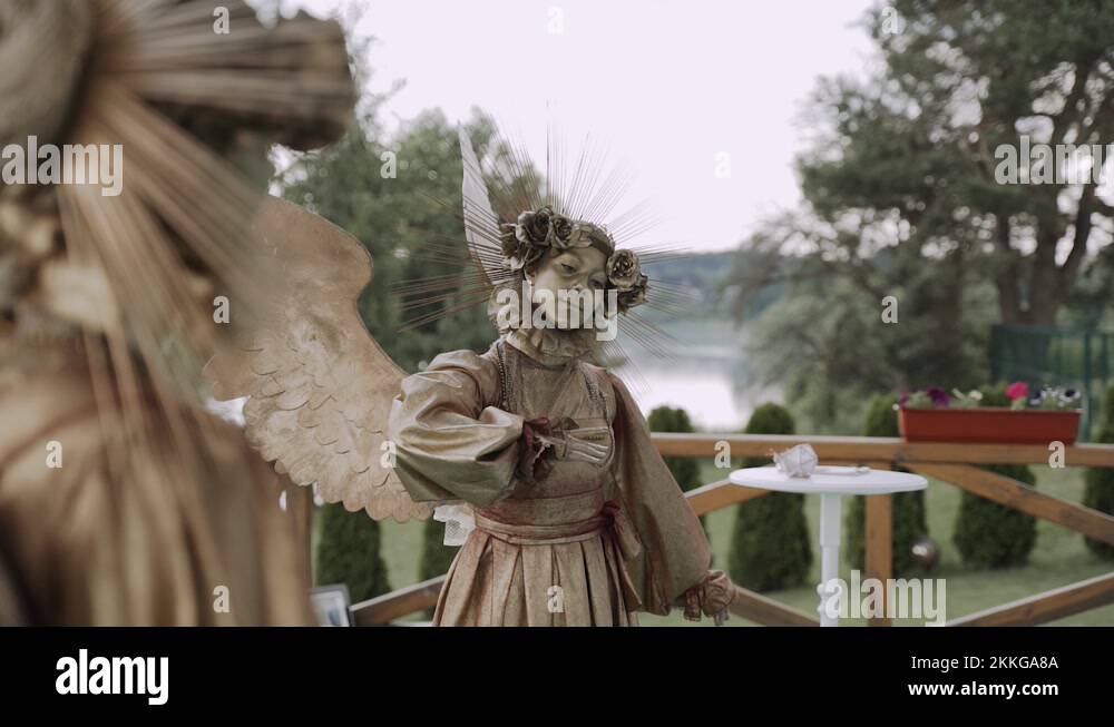 Living statue in form of golden angel stands in park and raises its ...