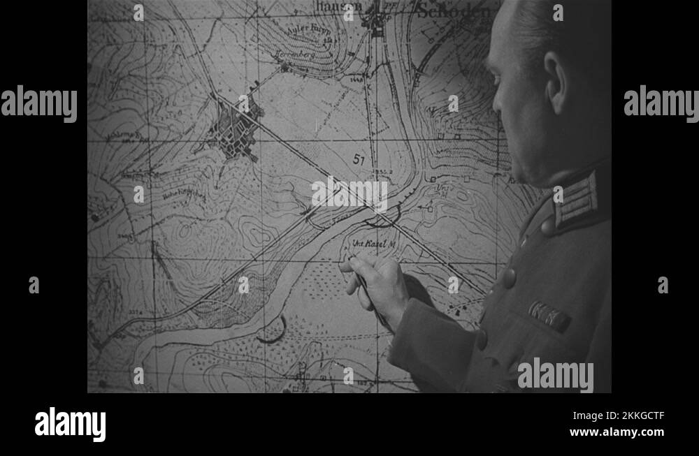 1940s: Army officer points at map on wall. Other officers watch him ...