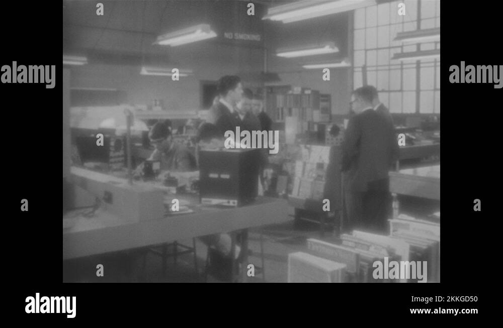 1960s: Man talks to four young men in radio tech lab. Young men listen ...