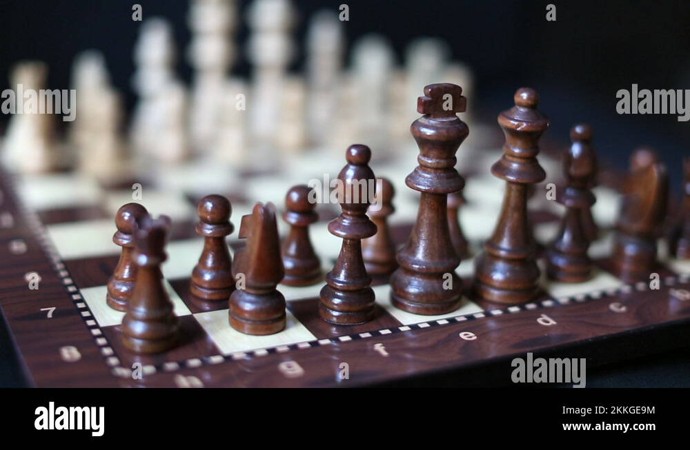 wooden white and black chess pieces on the board. blurry background ...