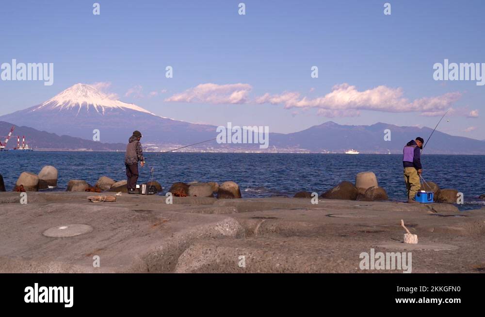 Two fishermen fishing at pier with backdrop of Mount Fuji - Slow motion ...