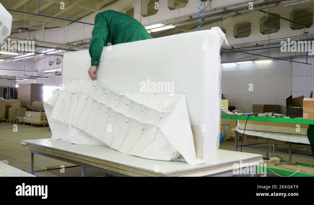 Worker dressed in uniform making a sofa, couch, settee in furniture ...
