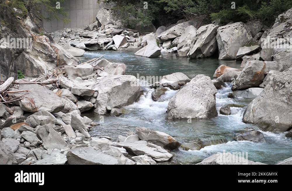 Clear blue water streaming true the rocks and green trees on the side ...