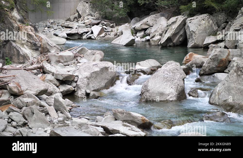 Clear blue water streaming true the rocks and green trees on the side ...