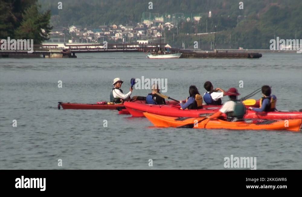 Tourists use canoes to visit the floating torii gate in Japan (zoom out ...