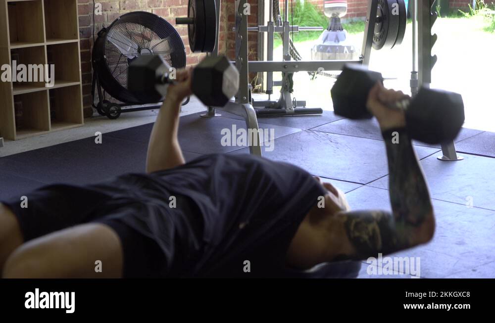 Tattooed man in home gym decline dumbbell bench press man blurry Stock ...