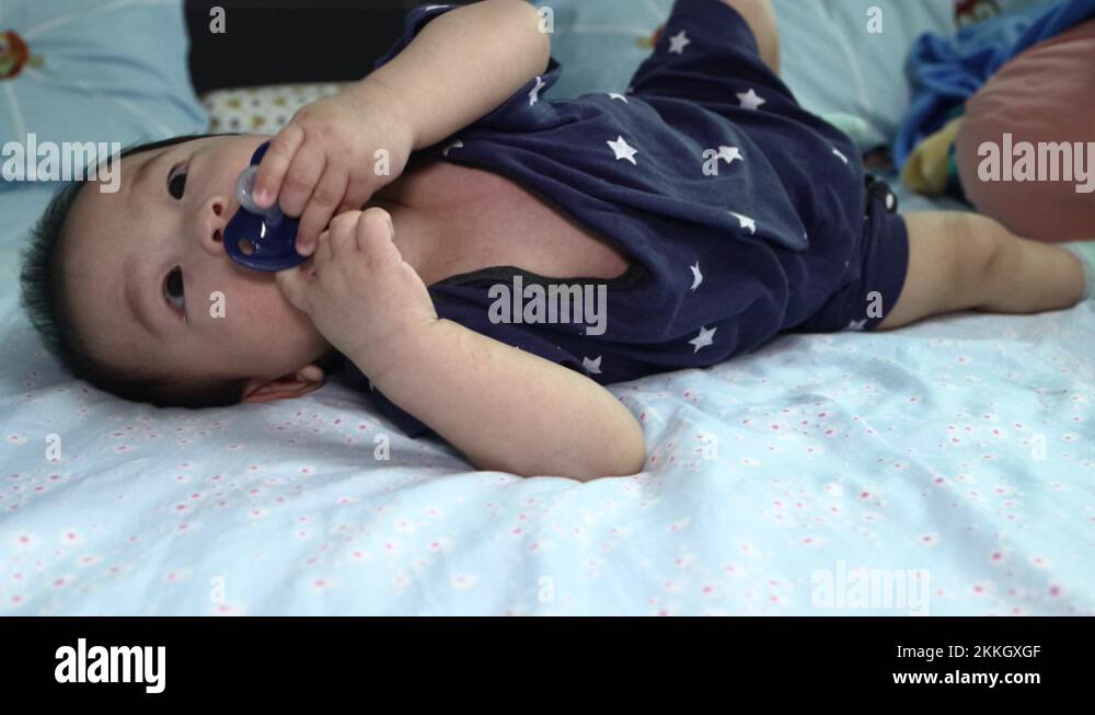 8 Month old Asian Chinese baby boy lying on bed with playing his pacifier Stock Video Footage ...