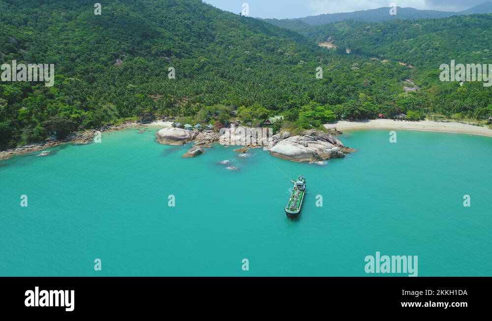 Thailand's ocean coast aerial: ship near huge boulder by white sandy ...