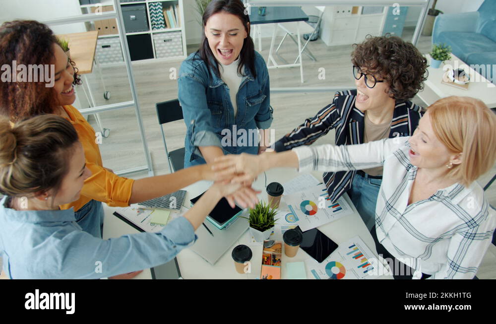 Multi-ethnic group of women joining hands then applauding and doing ...