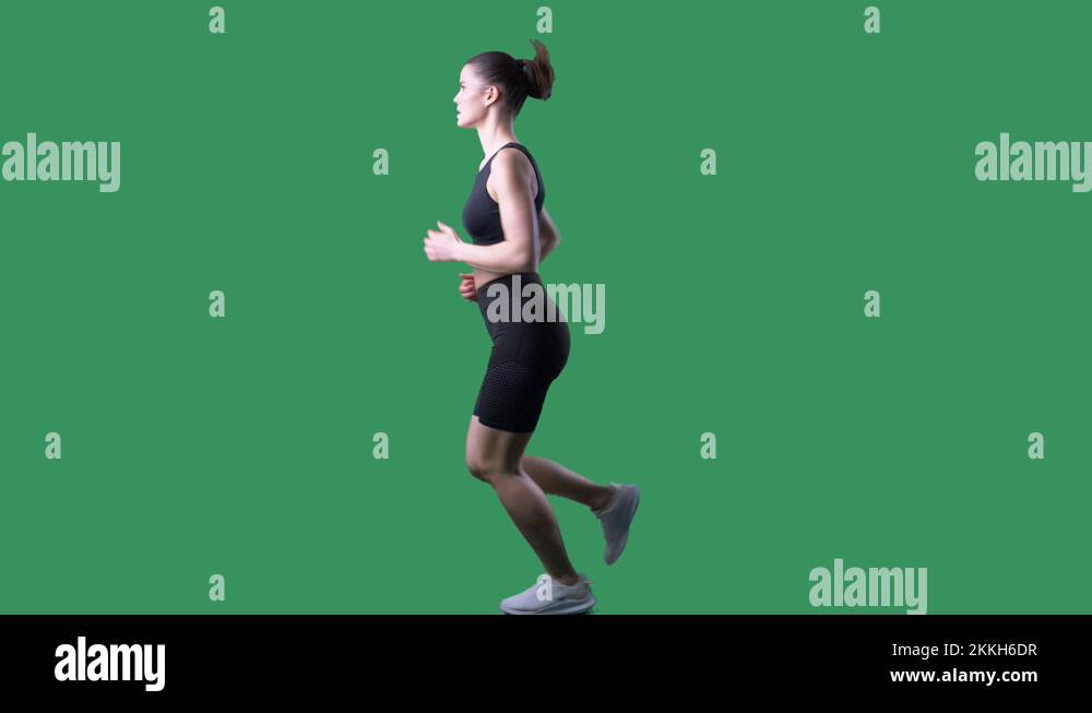 Side view of fit active woman running or jogging. Full body on green ...