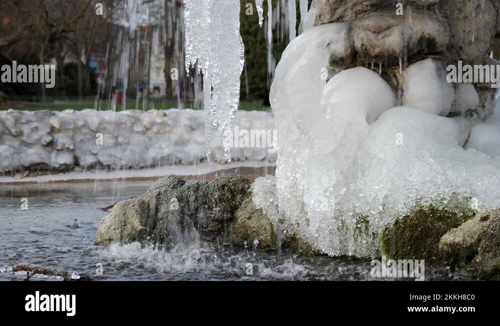 Water and ice flowing from a frozen public fountain in cold weather ...