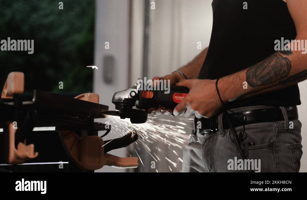 Male mechanic using power tool in workplace creating sparks from metal ...