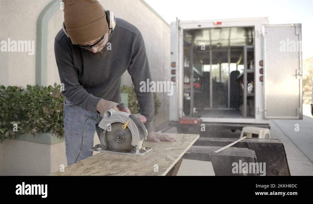 Carpenter using circular saw to cut wood plank or board outside Stock ...