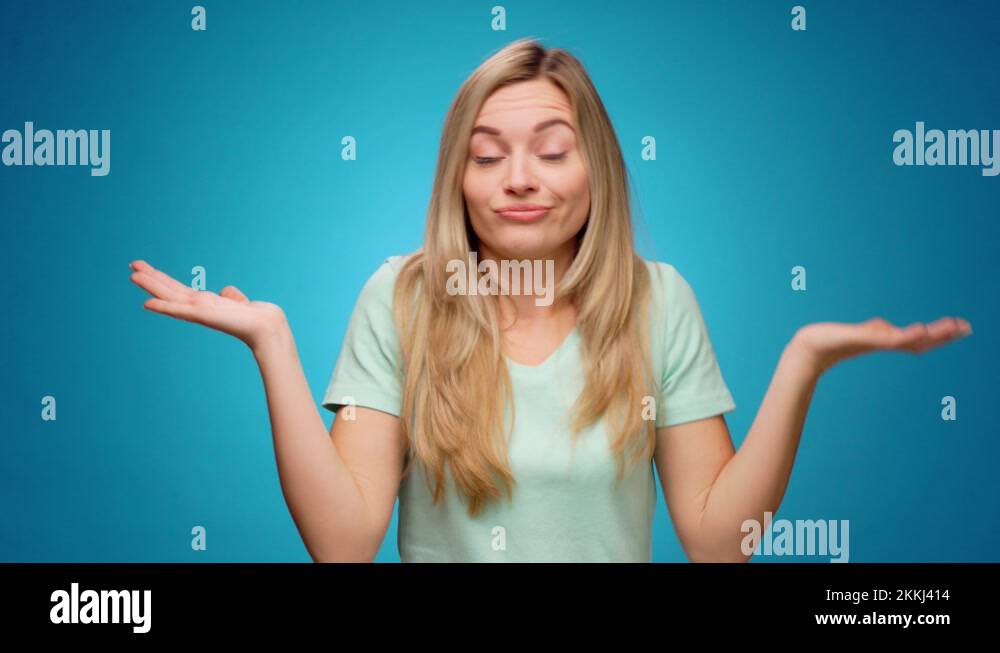Confused woman spreads her arms and shrugs shoulders, she doesn't know ...