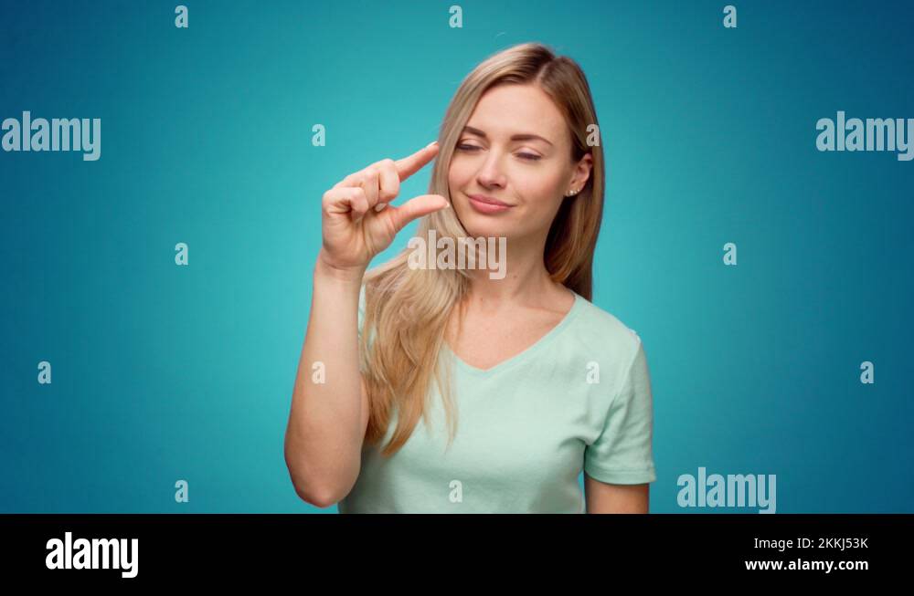 Disappointed young woman showing small size gesture against blue ...