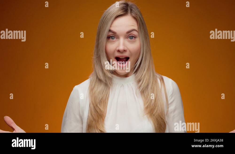 Surprised excited young woman expressing approval against yellow ...