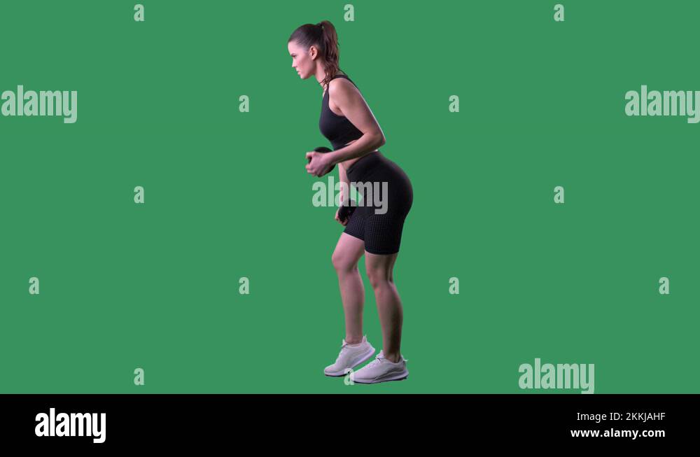 Side view of fit woman doing triceps kickback one arm exercise on green ...