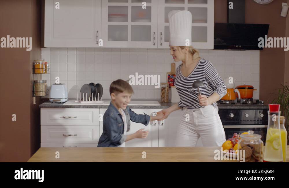 Young mom and son wearing chef hats dance in the kitchen Stock Video ...