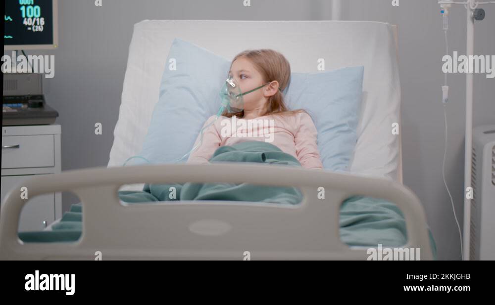 Girl suffering from pneumonia lying in a hospital bed with oxygen mask ...