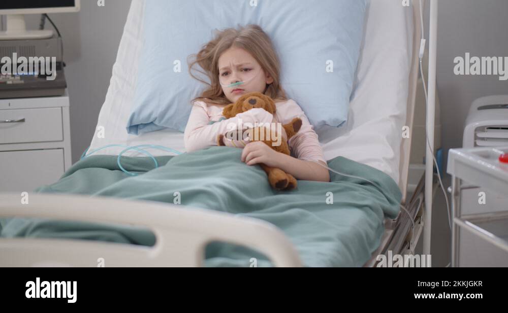 Portrait of sick girl hugging teddy bear lying in hospital bed Stock ...