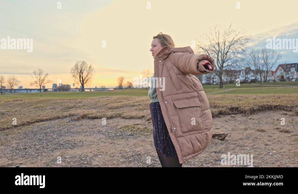 [4k] Young Woman Putting On Winter Coat Outdoor Facing Wind In Sunset