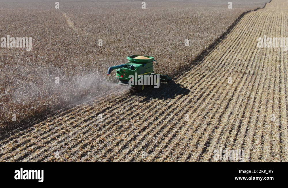Slow tilt up shot as combine harvester drives forward in the big vast ...