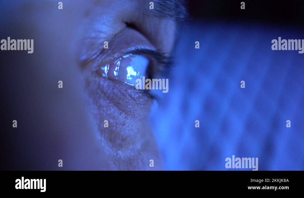 Close up a female eye watching something on the color changing screen ...