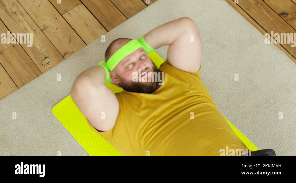 Fat man in yellow sportswear doing abs exercise crunches at home lying ...