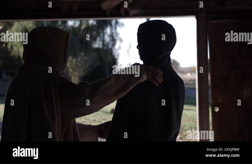 A man dressed as Jesus wearing a white, tattered robe and hood puts his ...