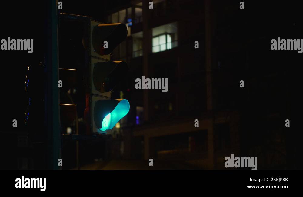 Steady Night time traffic light is green turns yellow then red in front ...