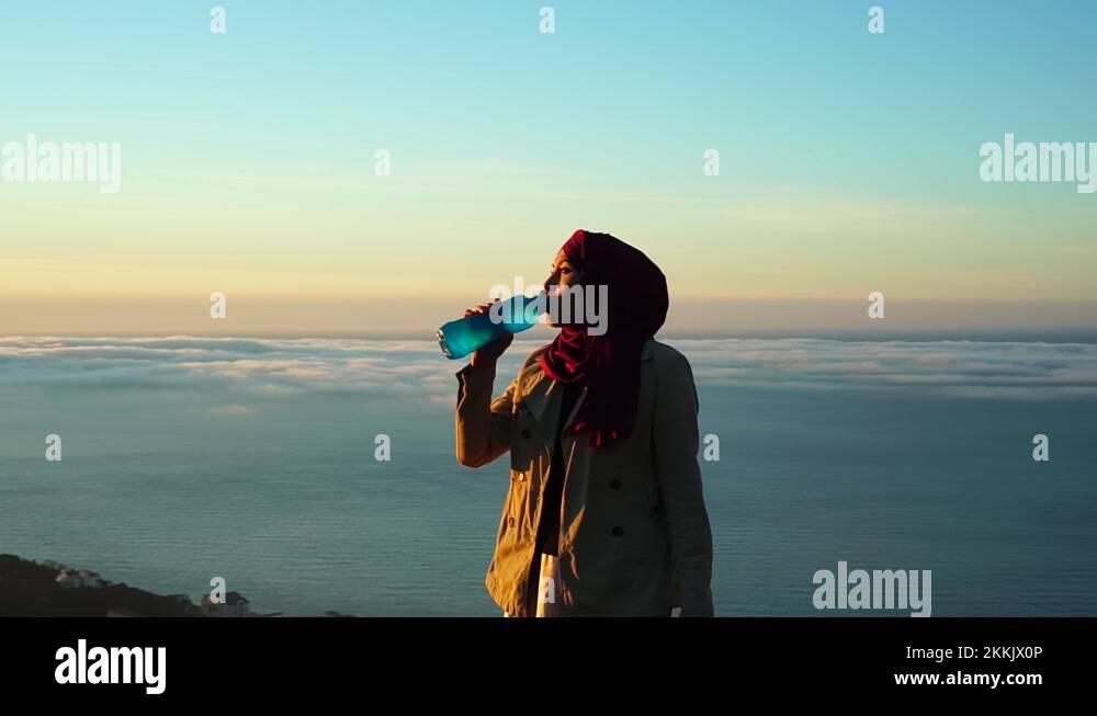 A muslim woman in a hijab drinks water from a reusable bottle. Zero ...