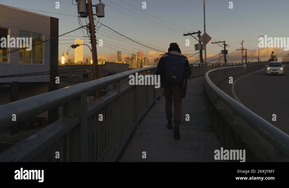 Following a pedestrian travelling man walking along the sidewalk ...