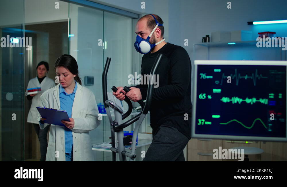 Monitor shows EKG reading of man athlete running on cross trainer Stock ...