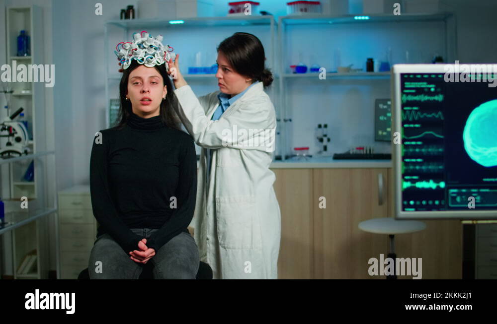 Medical lab technician adjusting eeg headset monitoring brain functions ...