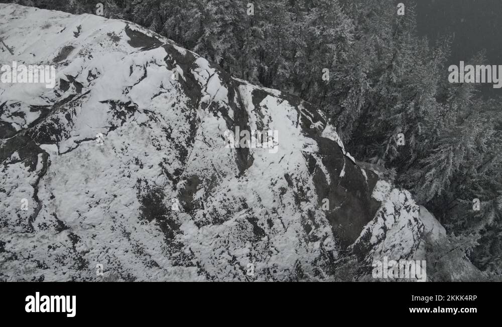 Snowflakes falling down on Quarry rocks and green pine trees creating a ...