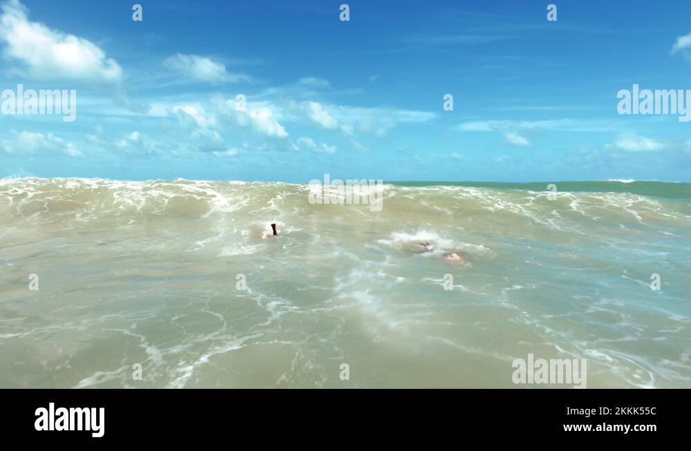 People diving under a forming wave as it approaches in the beautiful ...