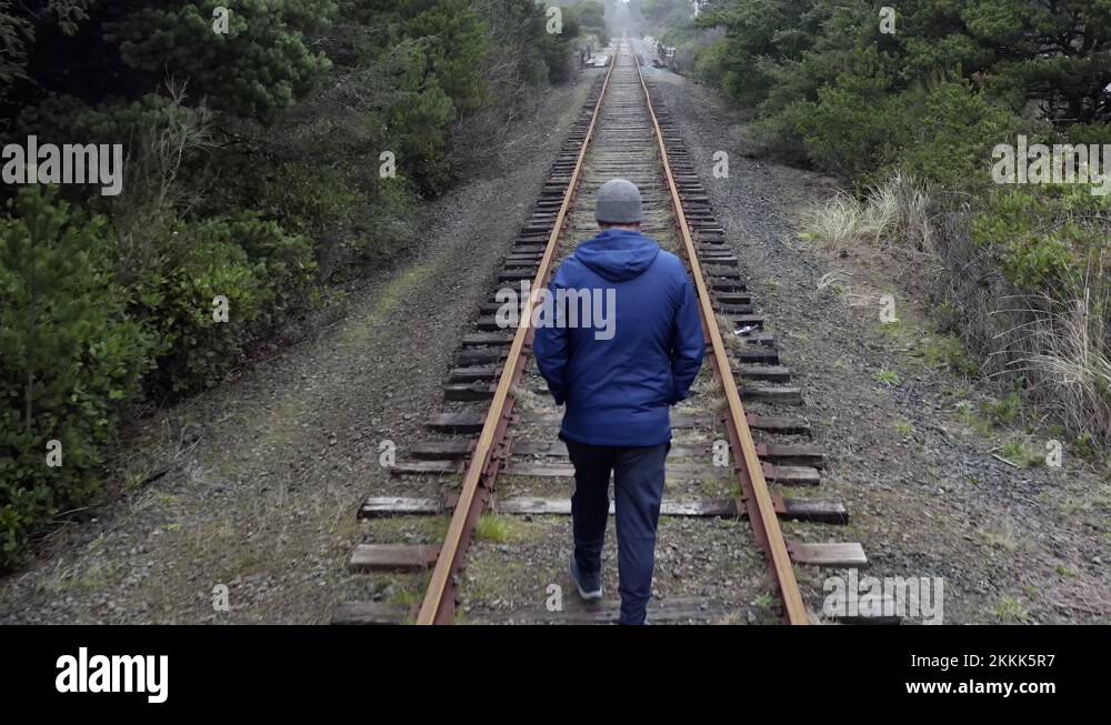 Back view of man walking alone on railroad tracks Stock Video Footage ...