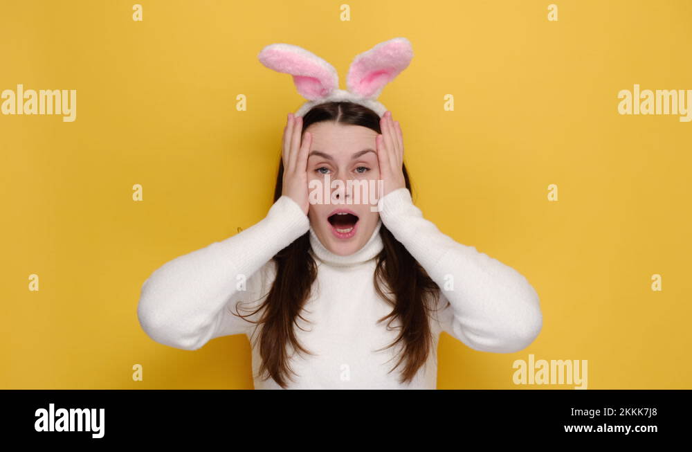 Shocked young female bunny fluffy ears say wow put hands on cheeks head ...
