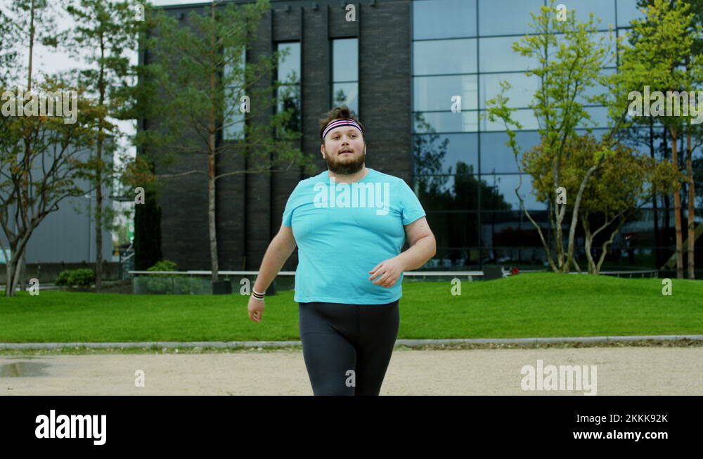Handsome fat young man beside of modern building in front of the camera ...