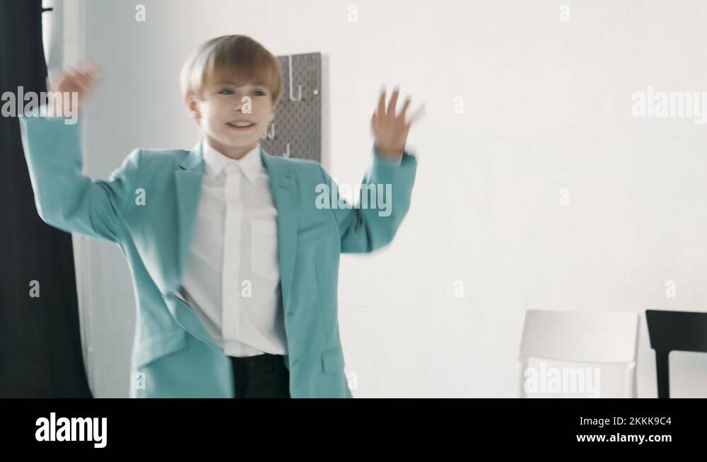 Funny happy cute little schoolboy dancing in classroom in good mood ...