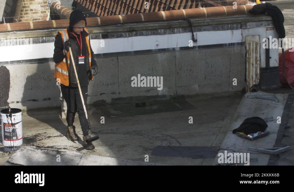 Male Workman Applying Bitumen Mastic On Roof Flat Of Building In London ...