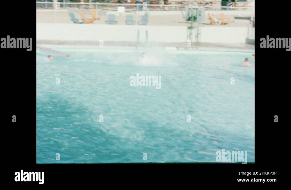 1950s: People swimming and playing in an outdoor pool. Child slides ...
