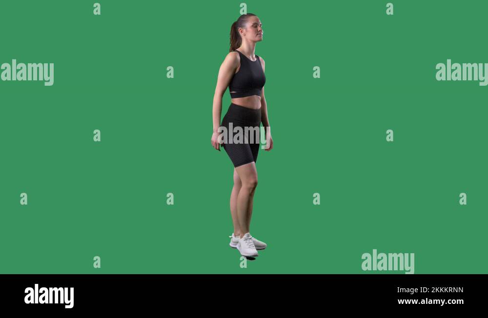 Fitness woman turning to camera and crossing arms. Full body on green ...