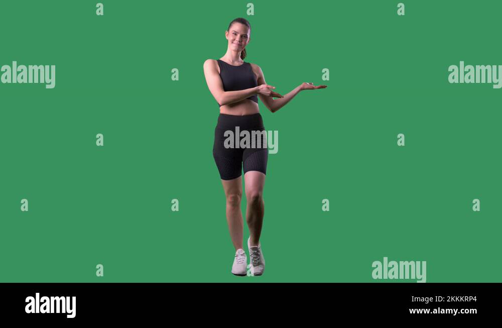 Fitness woman welcoming gesture at gym entrance. Full body on green ...