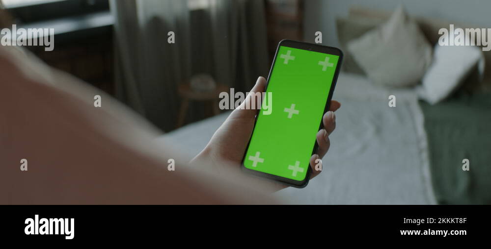 GREEN SCREEN CHROMA KEY Caucasian female using her phone, scrolling and ...