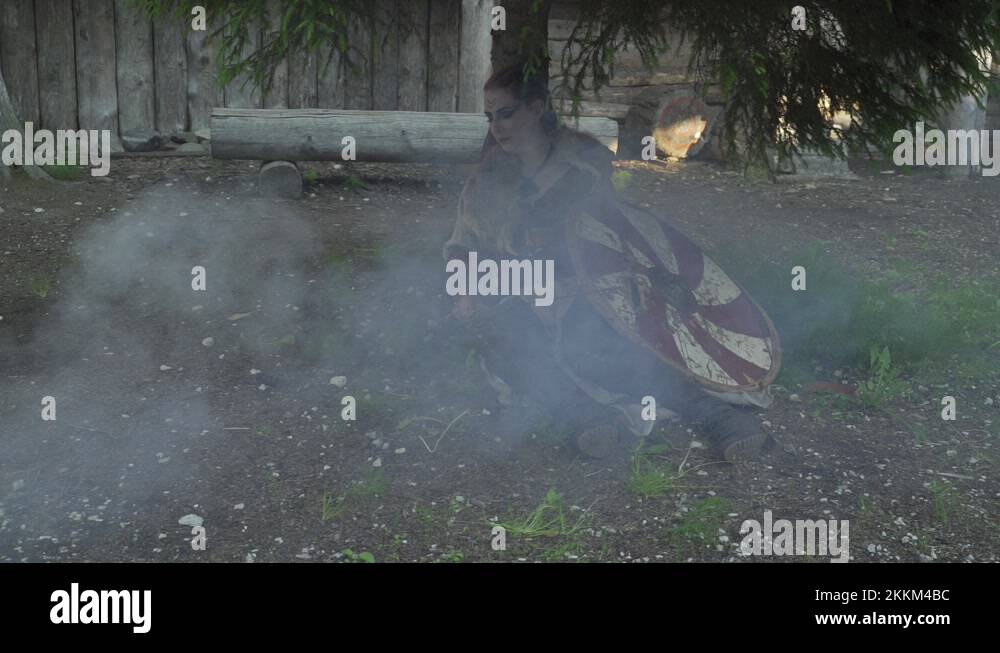 Viking warrior girl lies on a spruce tree and dies. Hand with the sword ...