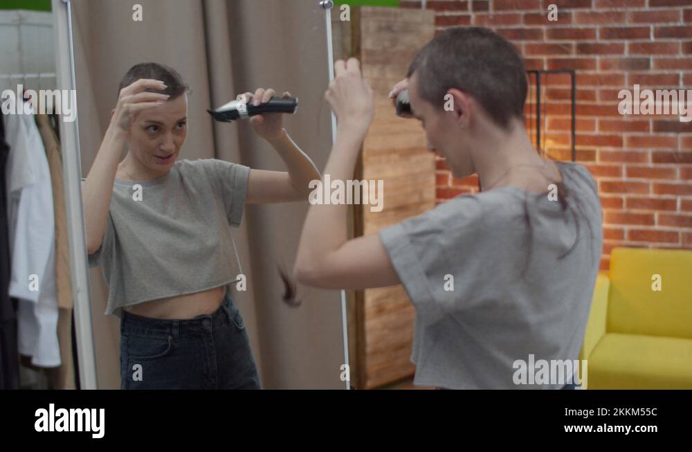 Woman shaves her head bald with a hair machine. The woman is happy to change Stock Video Footage ...