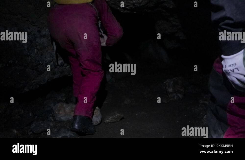Two people walking through the dark tunnels of a cave. Caving ...