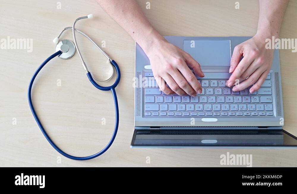 Top view of hands on the keyboard. Woman doctor at the desk typing on a ...
