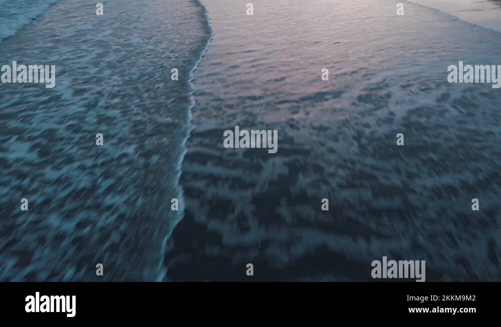 Fast drone flying backwards over water at Kai Iwi Beach during sunset ...